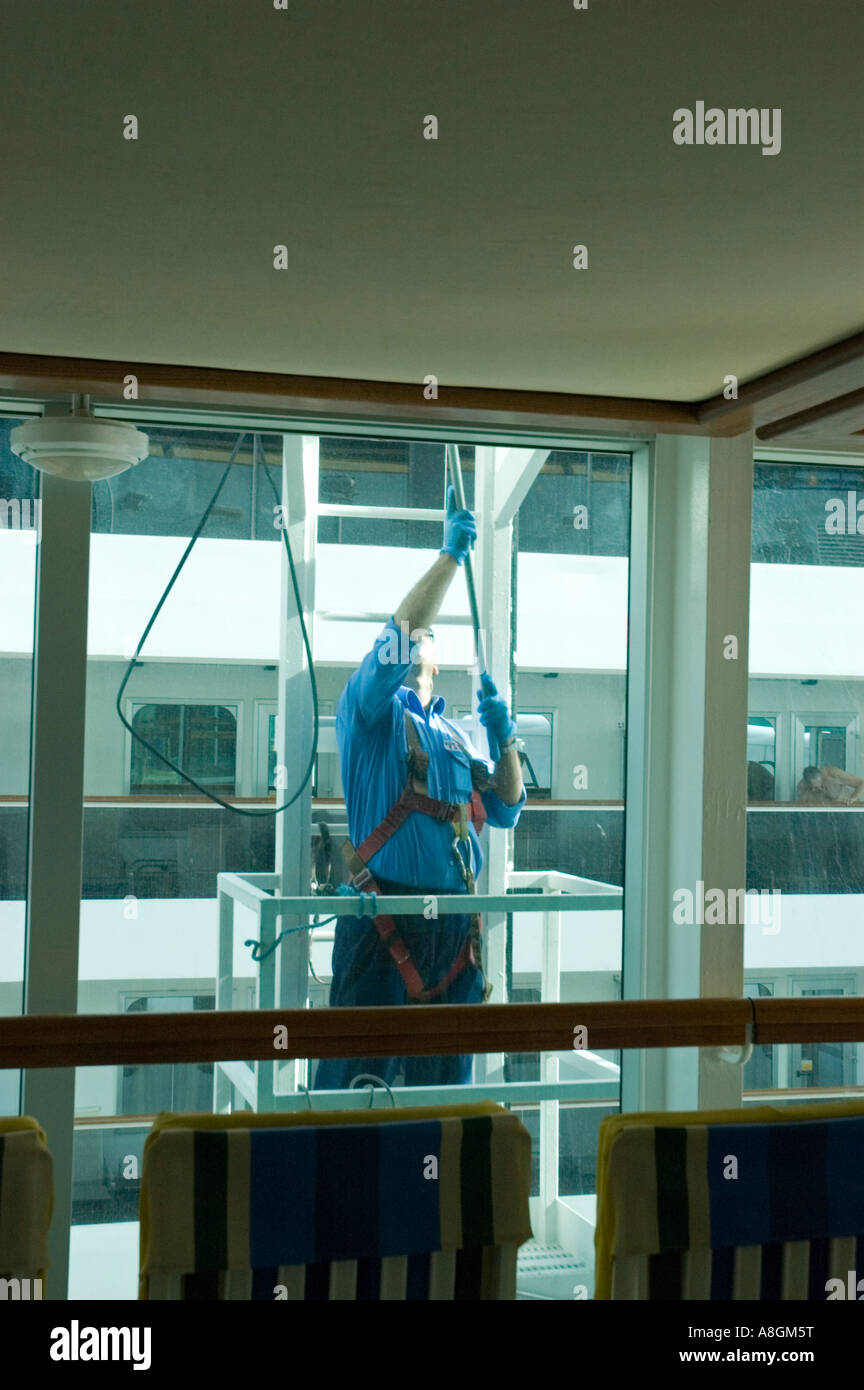 A crew member wears safety harness while working at height cleaning the ...