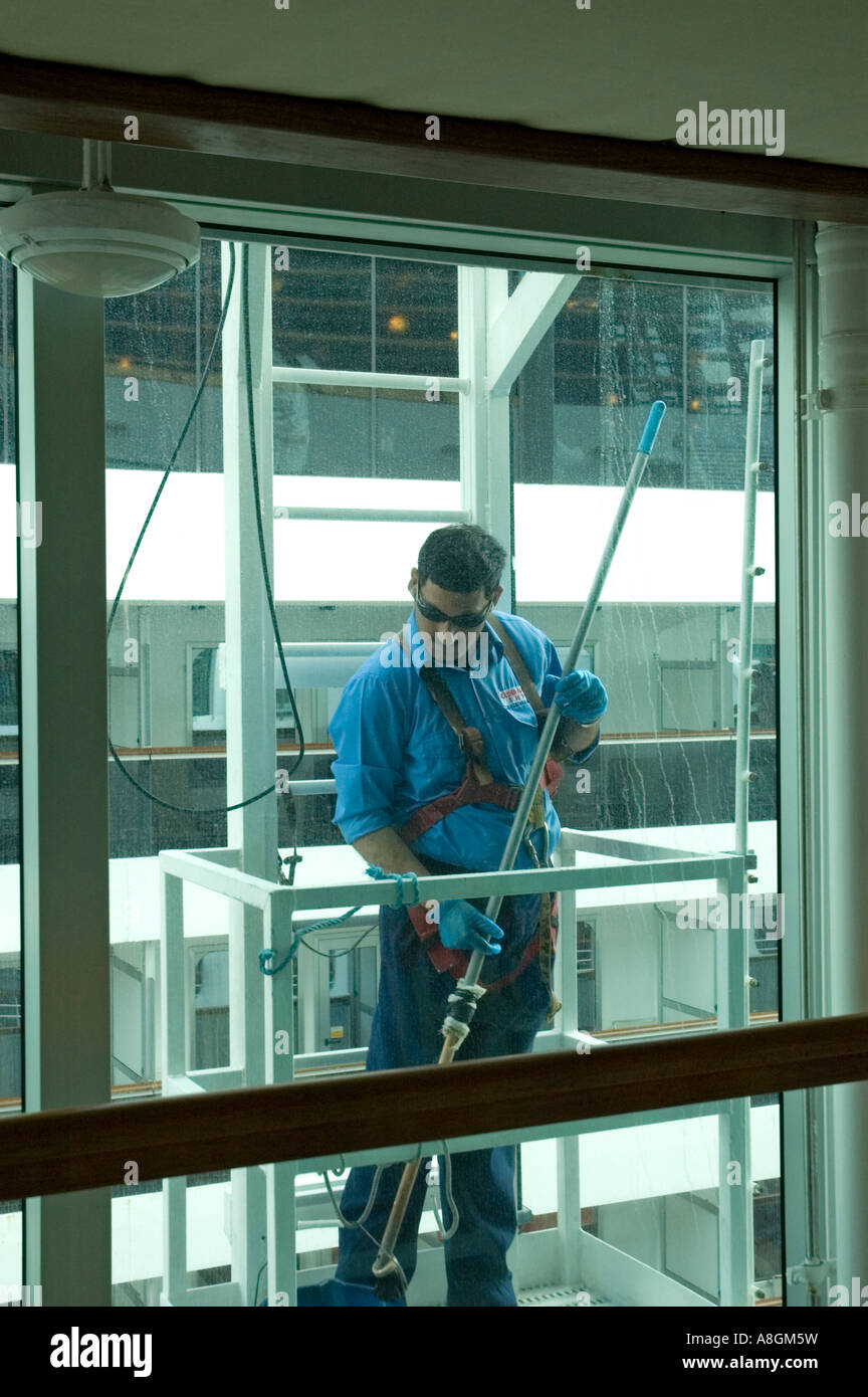 A crew member wears safety harness while working at height cleaning the ...