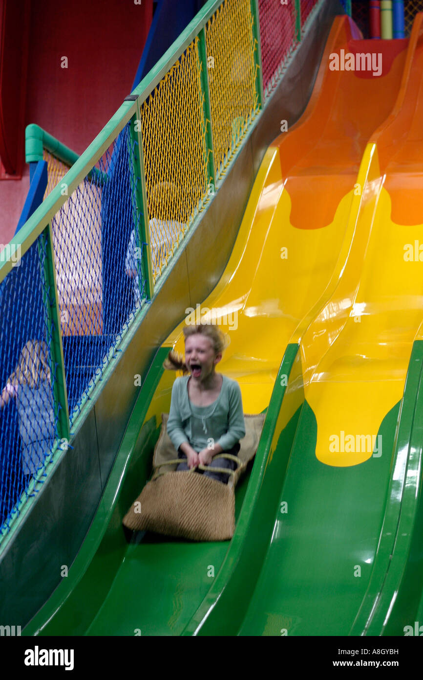 Girl whizzing down a coloured slide in an indoor play centre Stock ...