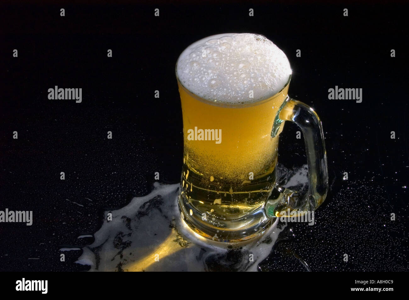 Studio still life overflowing beer mug Stock Photo - Alamy