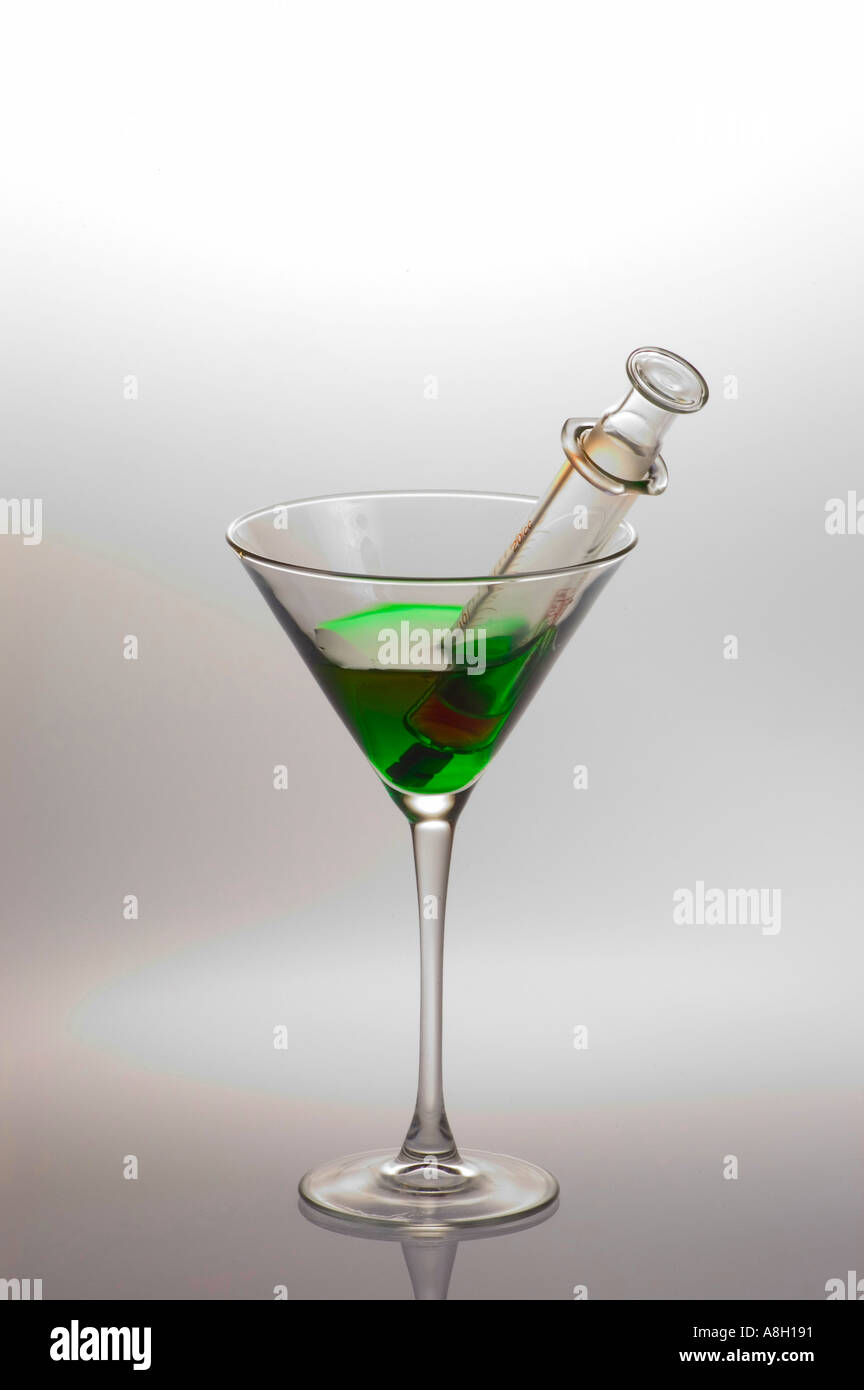 Loaded hypodermic syringe used as stirrer in Martini glass with green ...