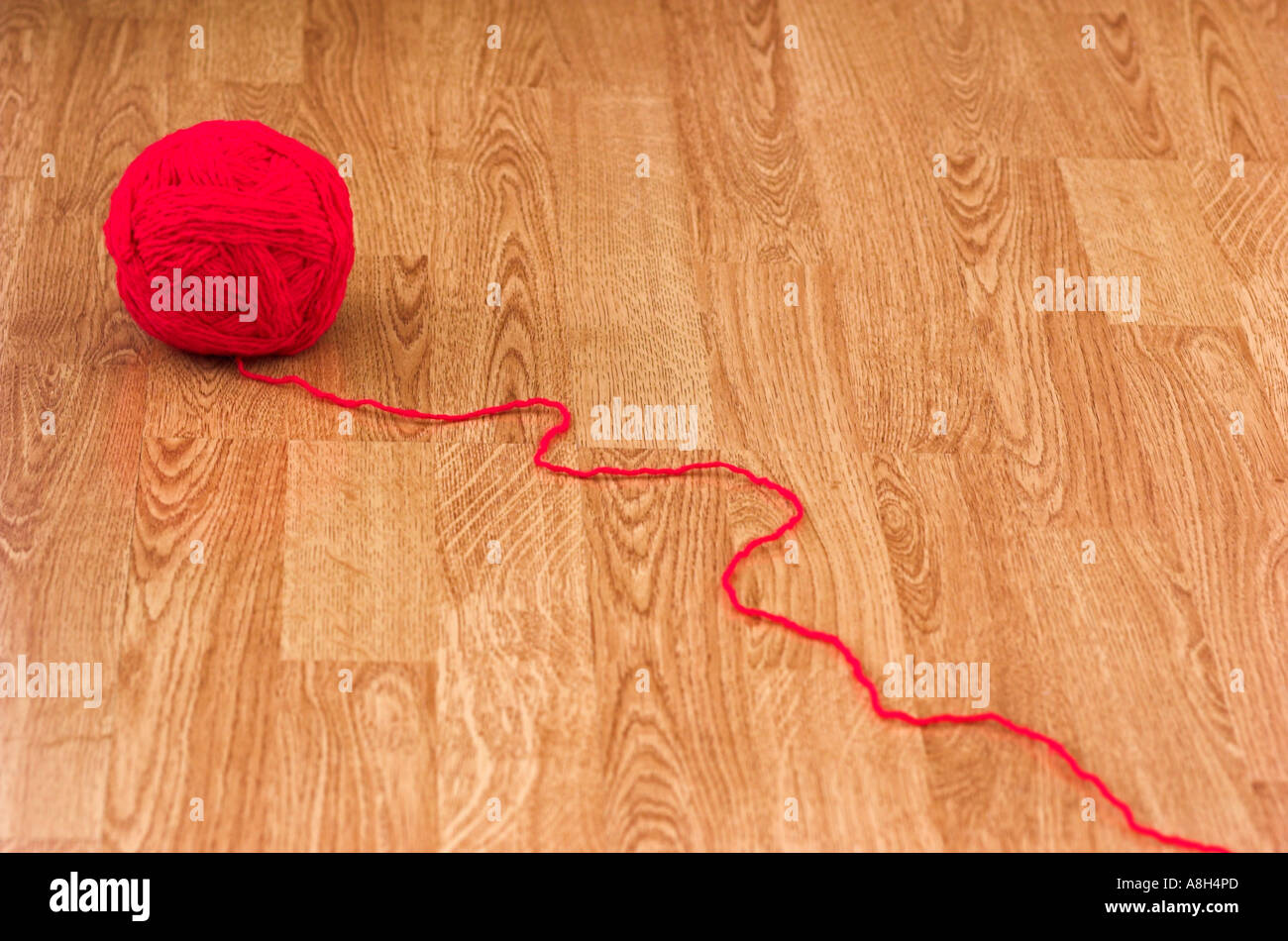 Ball of red wool on floor Stock Photo - Alamy