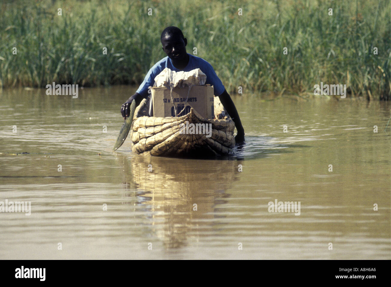 Njemps schoolboy paddling his ambach canoe loaded with a carton of Omo ...