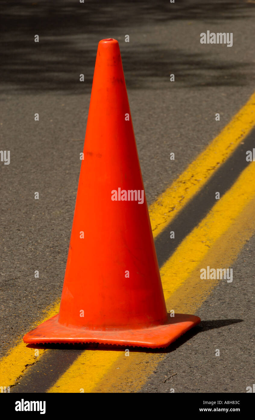 Orange road cone standing on double yellow line in roadway Stock Photo ...