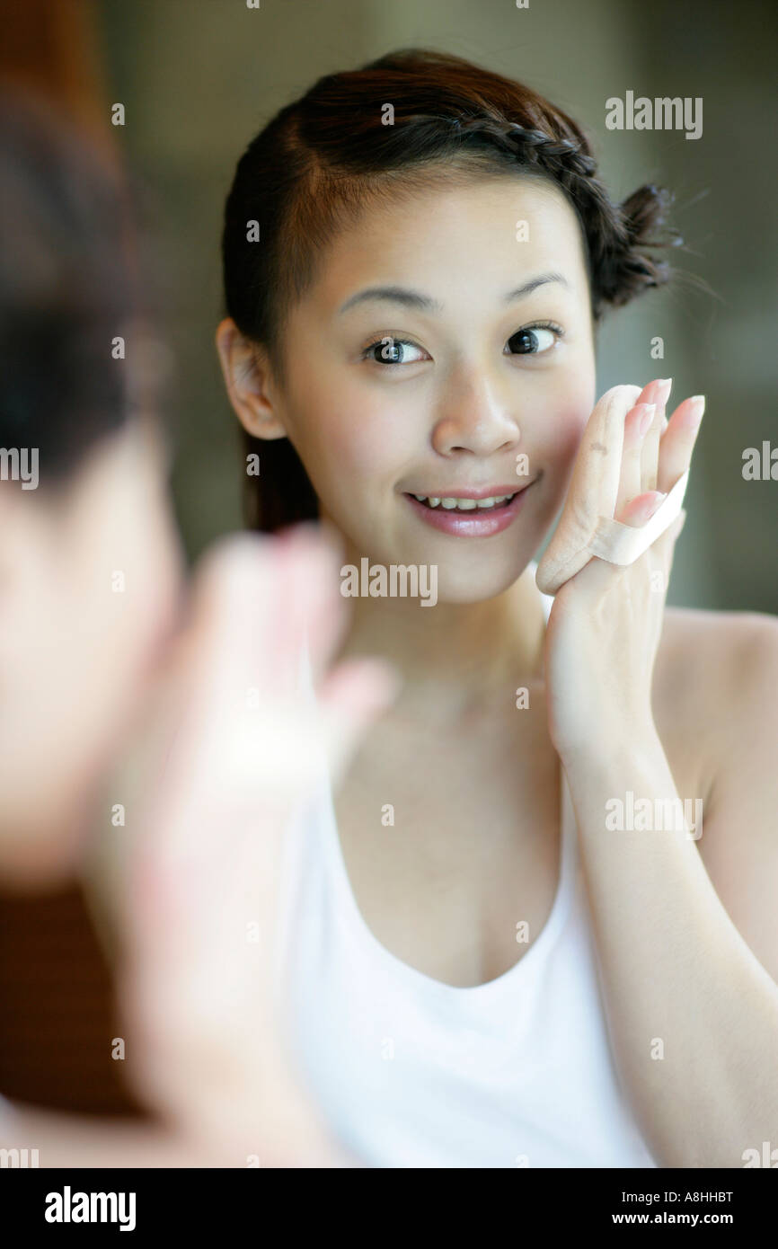 Woman applying powder puff on her cheeks Stock Photo - Alamy