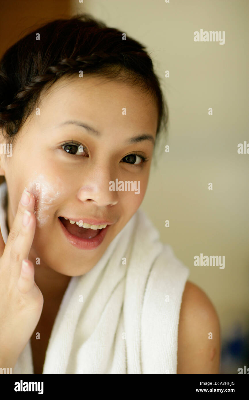 Portrait of a young woman applying cream Stock Photo - Alamy