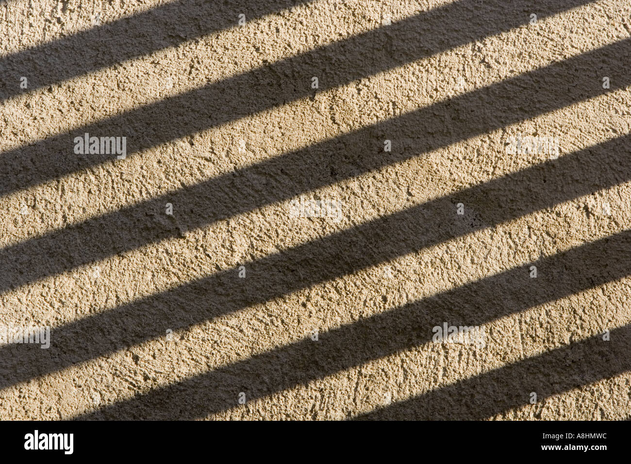 Diagonal lines of shadows cast by gate on to a wall Stock Photo - Alamy
