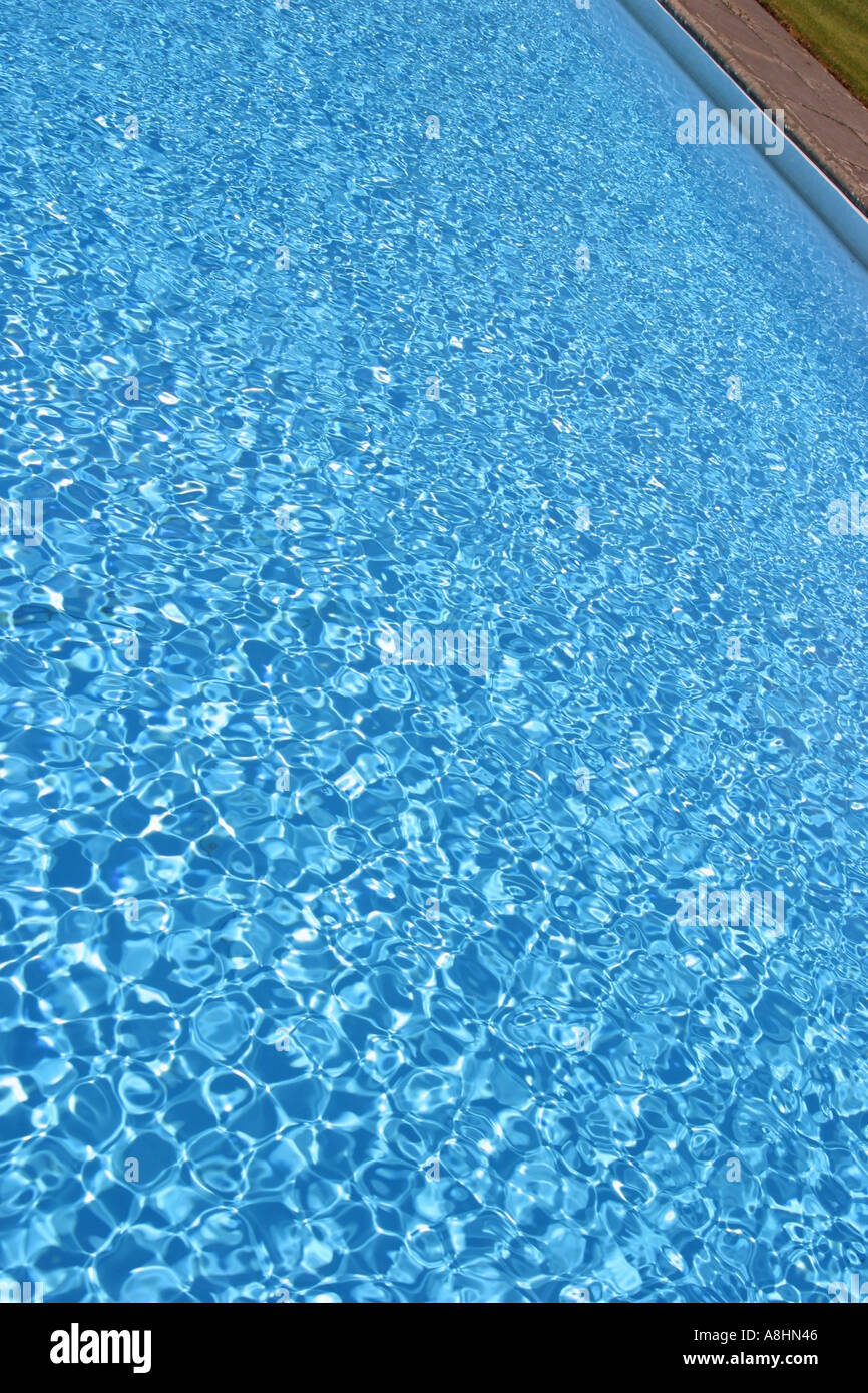 Sunshine reflecting on the surface of a private swimming pool with edge ...