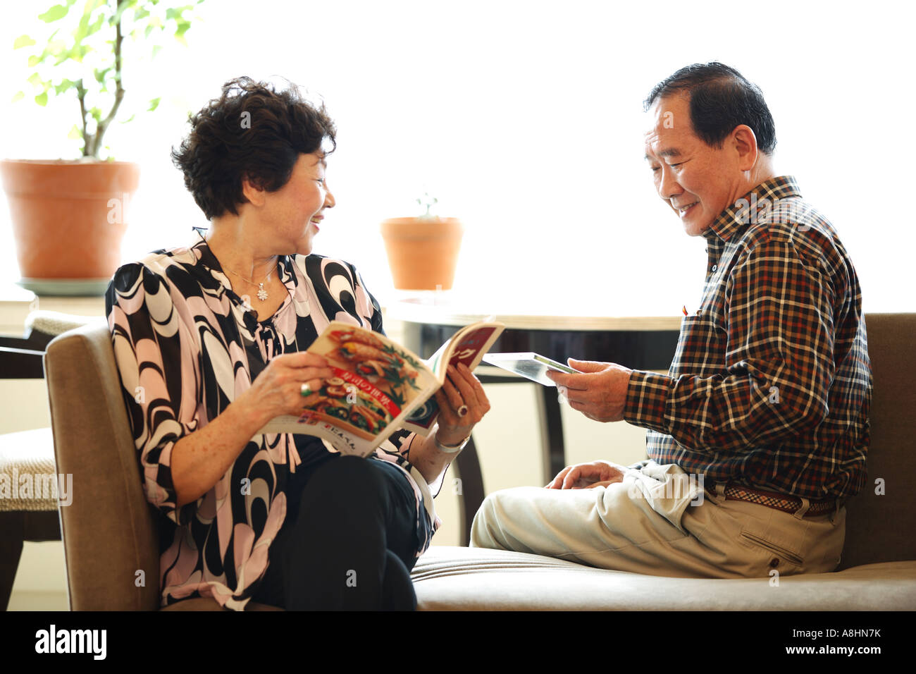 View of a couple sitting reading paper Stock Photo - Alamy