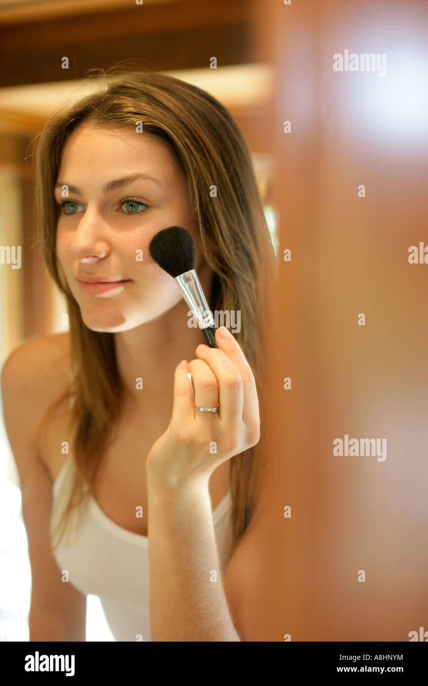 Young woman applying blusher on cheeks Stock Photo - Alamy