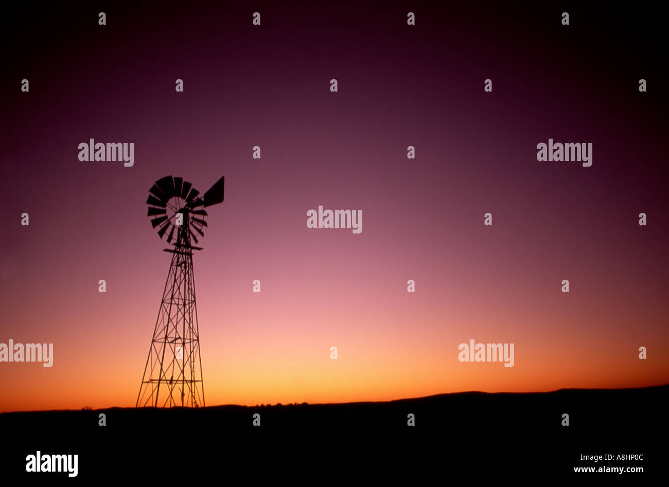 Wind water well silhouetted against the dawn horizon Australian outback ...