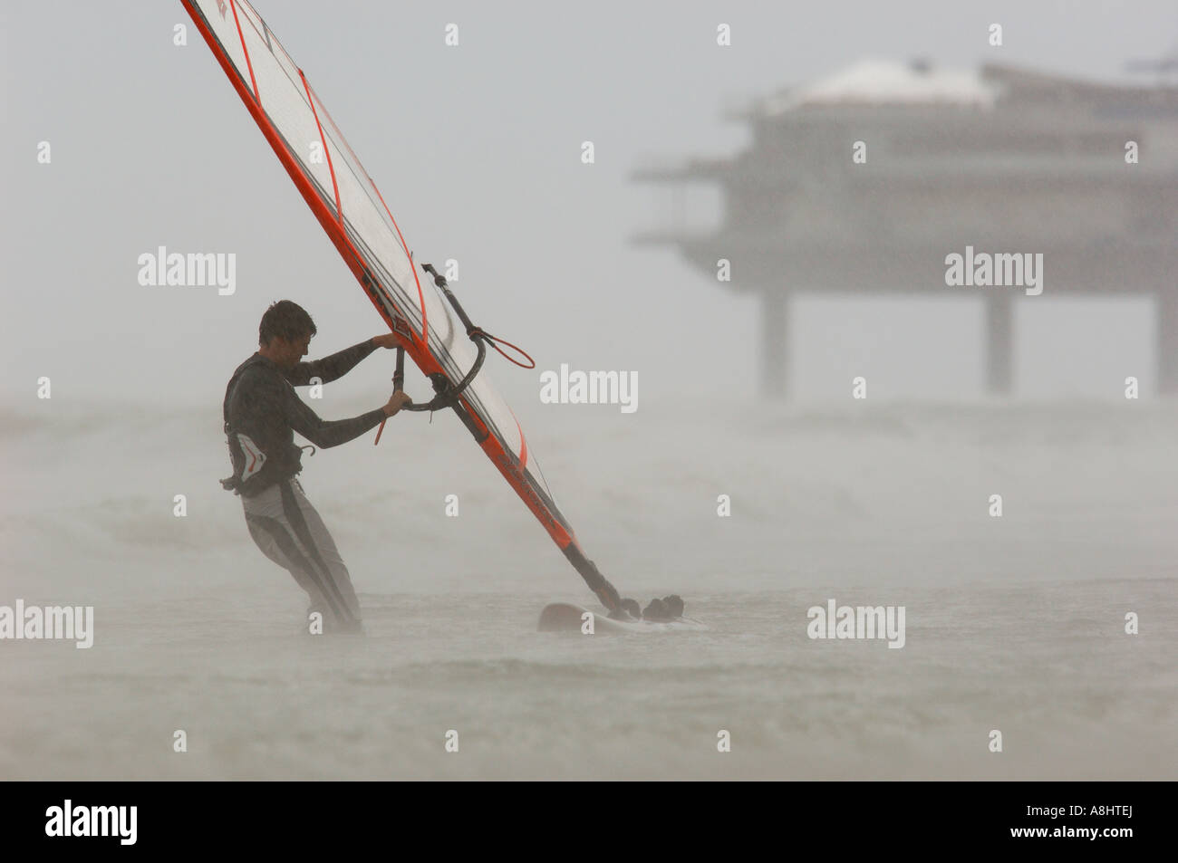 Windsurf people men on the beach with storm and rain on the coast by ...