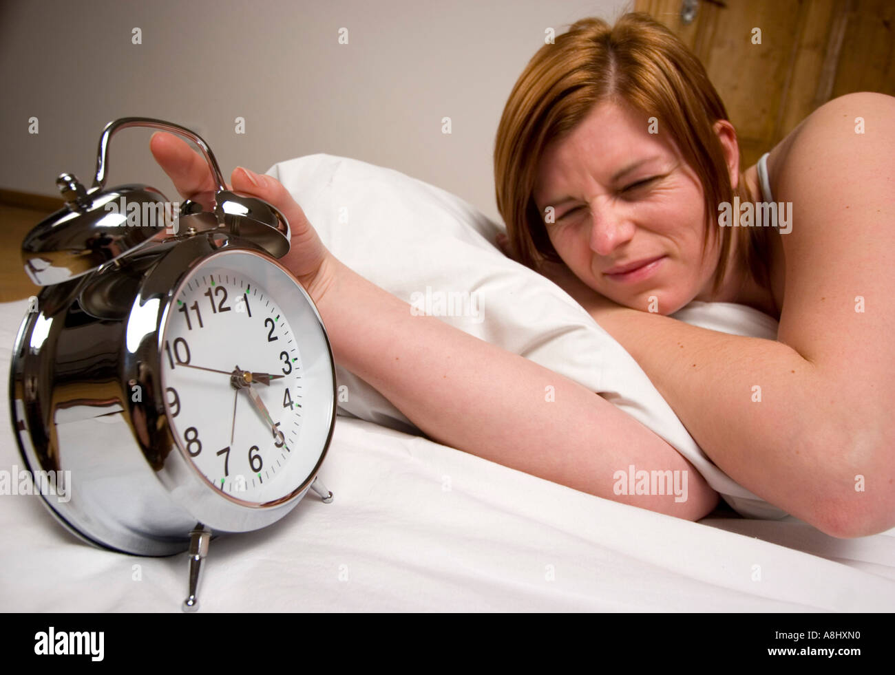 Woman looking at alarm clock Stock Photo - Alamy