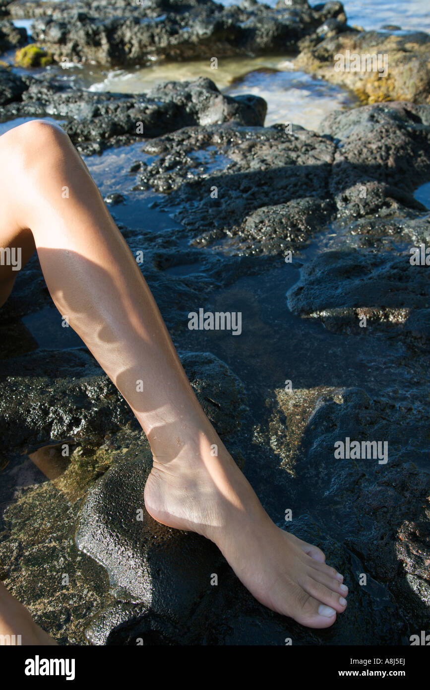 Leg and foot of young adult Asian Filipino female on rocks on beach in ...