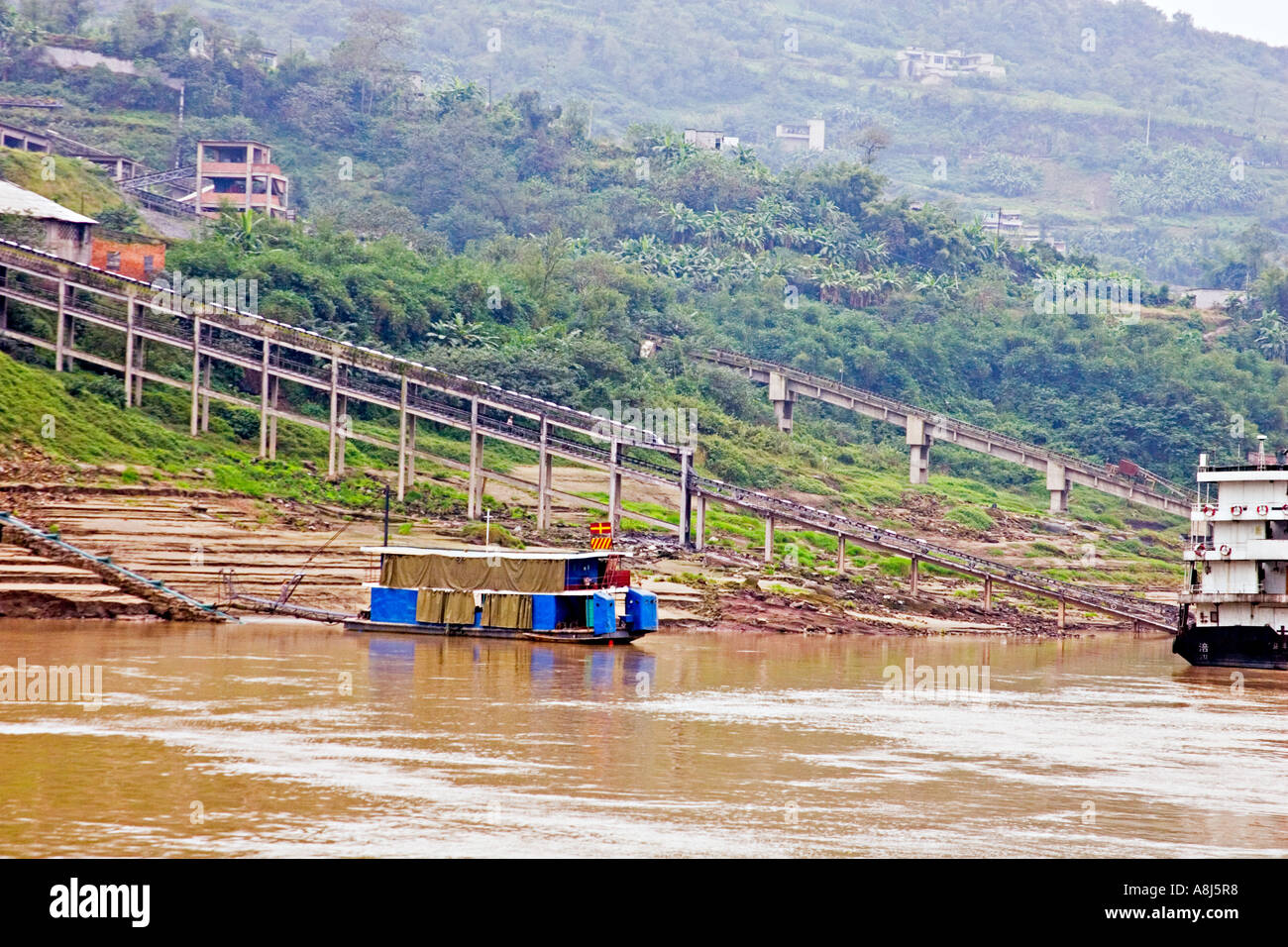CHINA YANGTZE RIVER Conveyer belt loads barges with white bags of lime ...