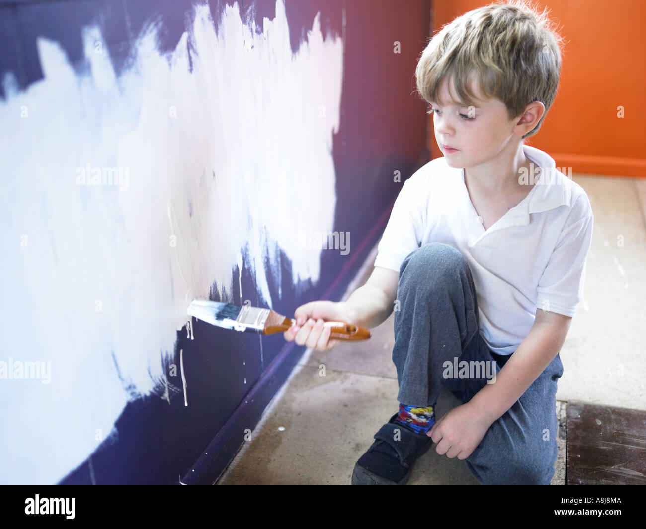 young child holding a paintbrush getting involved in repainting his ...