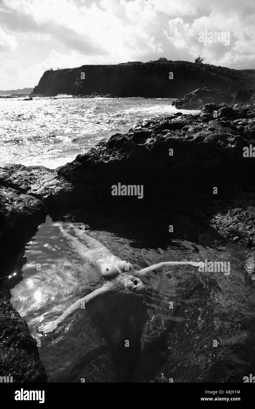 Young Nude Asian Woman Floating In Water With Arms Outstretched In Maui