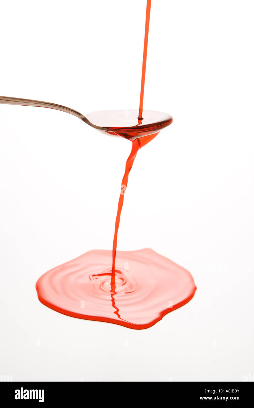 Stream of red cough syrup overflowing spoon into puddle below Stock ...