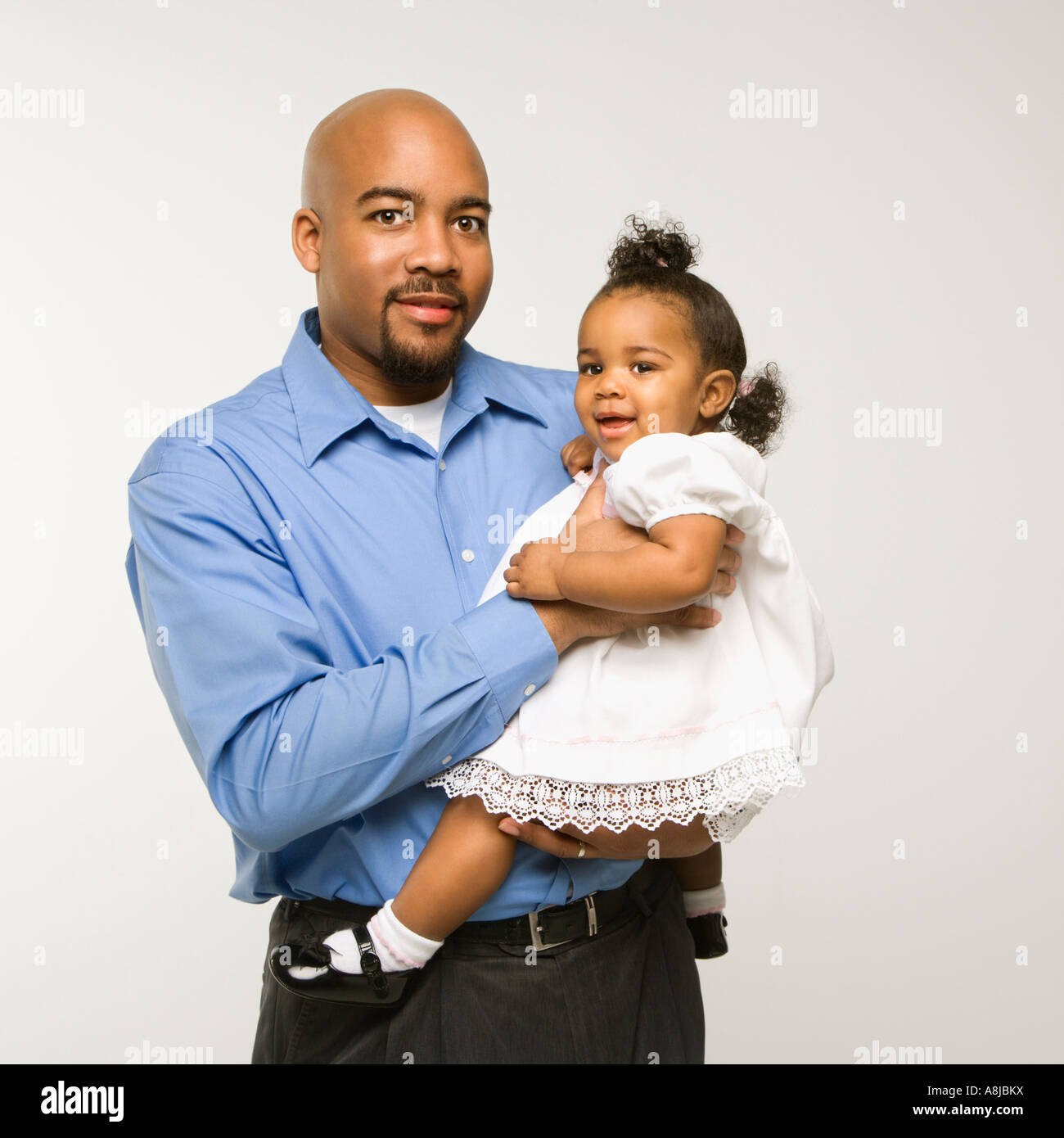 African American man holding infant girl standing against white ...