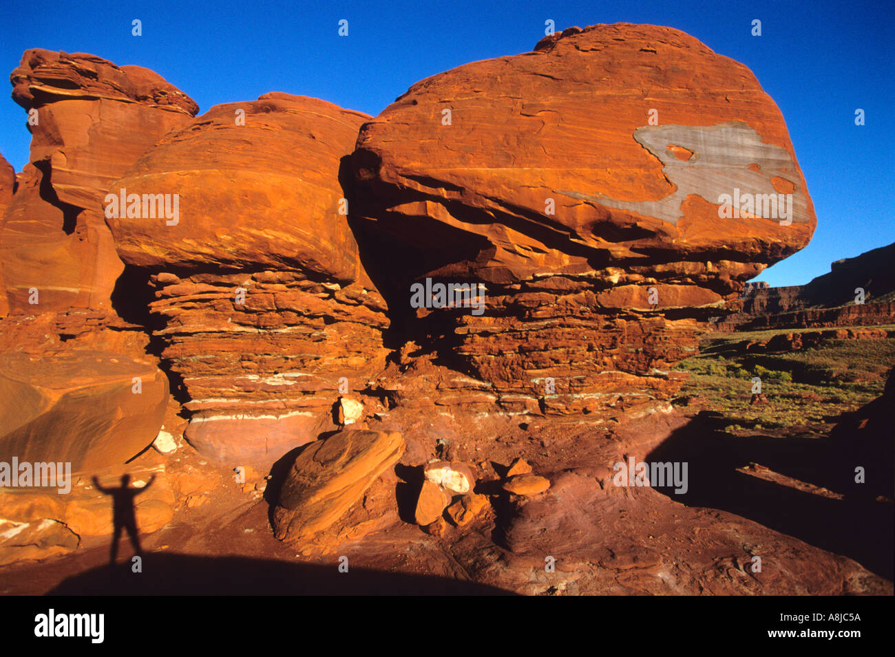 shadow of a man waiving on a red rock landscape near Moab Utah USA ...