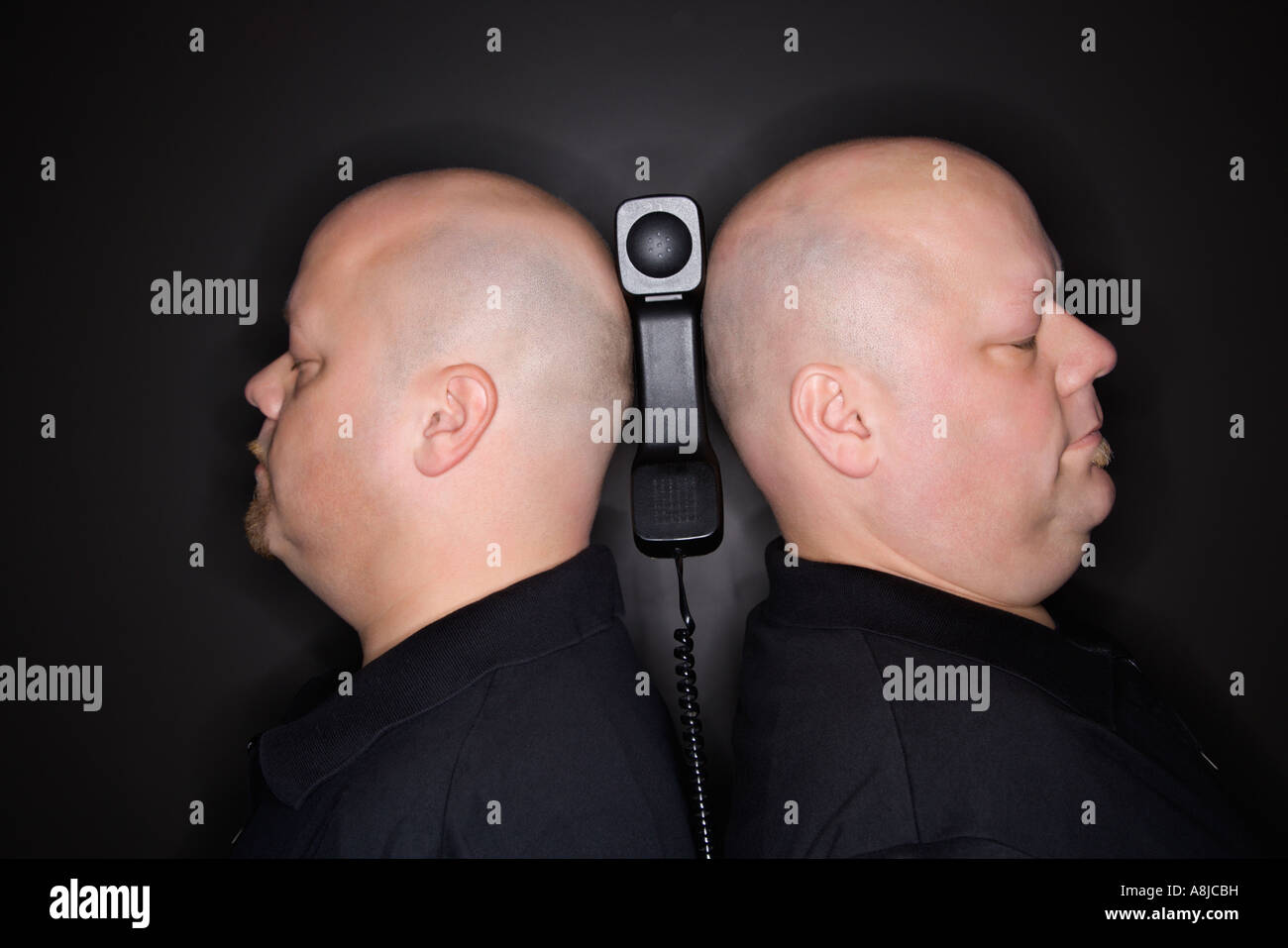 Caucasian mid adult identical twin men standing back to back with ...