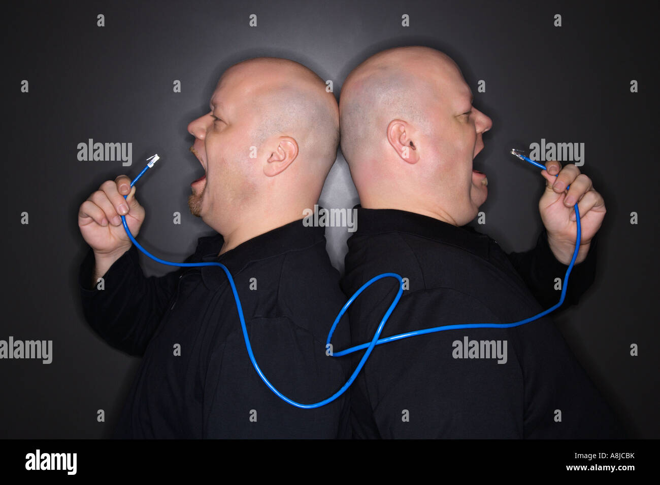 Caucasian bald mid adult identical twin men standing back to back ...