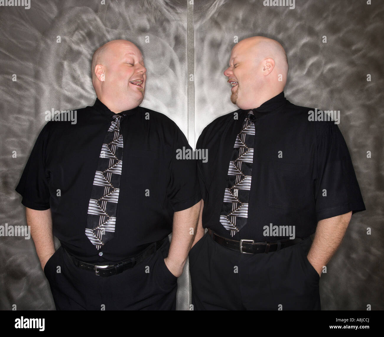 Caucasian bald mid adult identical twin men looking at each other ...