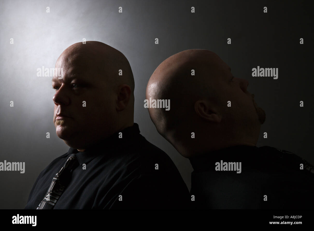 Caucasian mid adult bald identical twin men standing back to back Stock ...