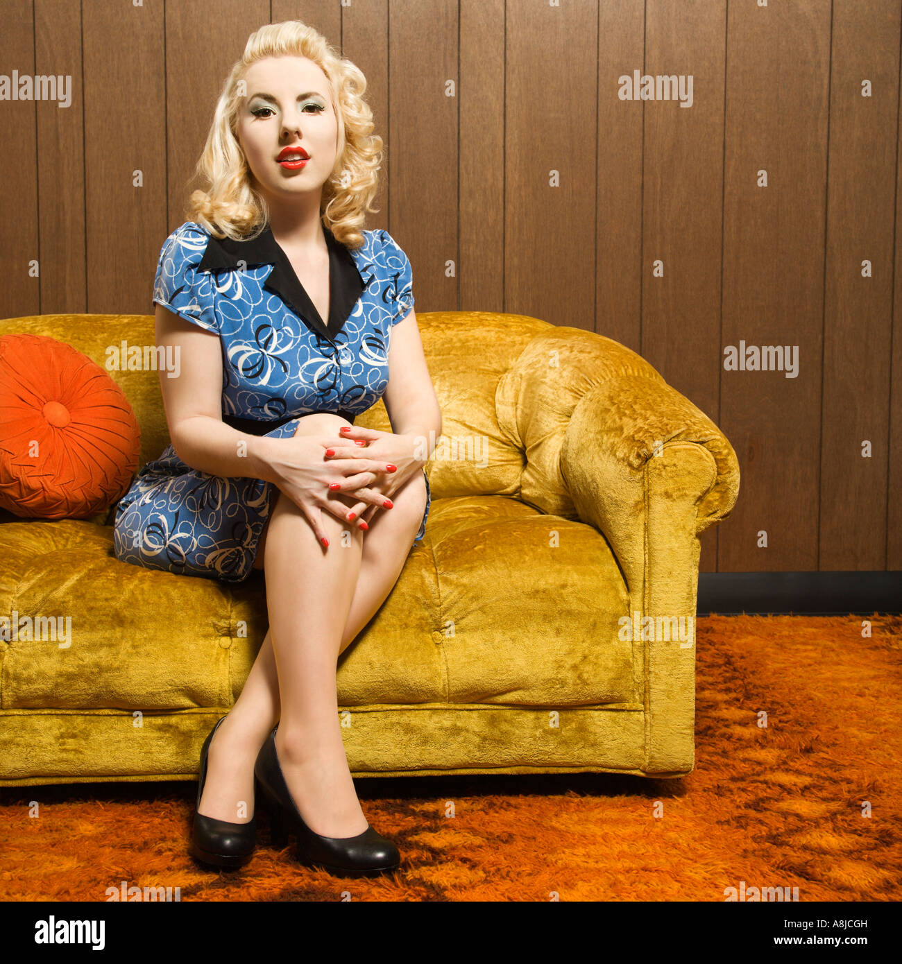 Attractive Caucasian woman sitting on retro style couch Stock Photo - Alamy