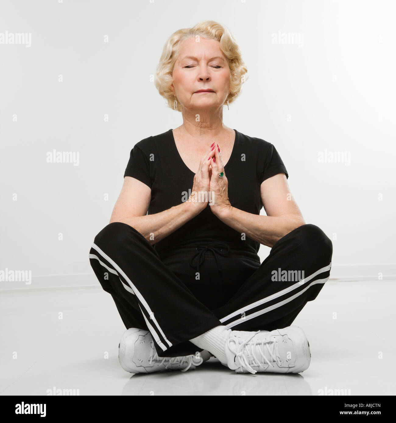 Caucasian senior woman sitting in yoga position on floor meditating ...