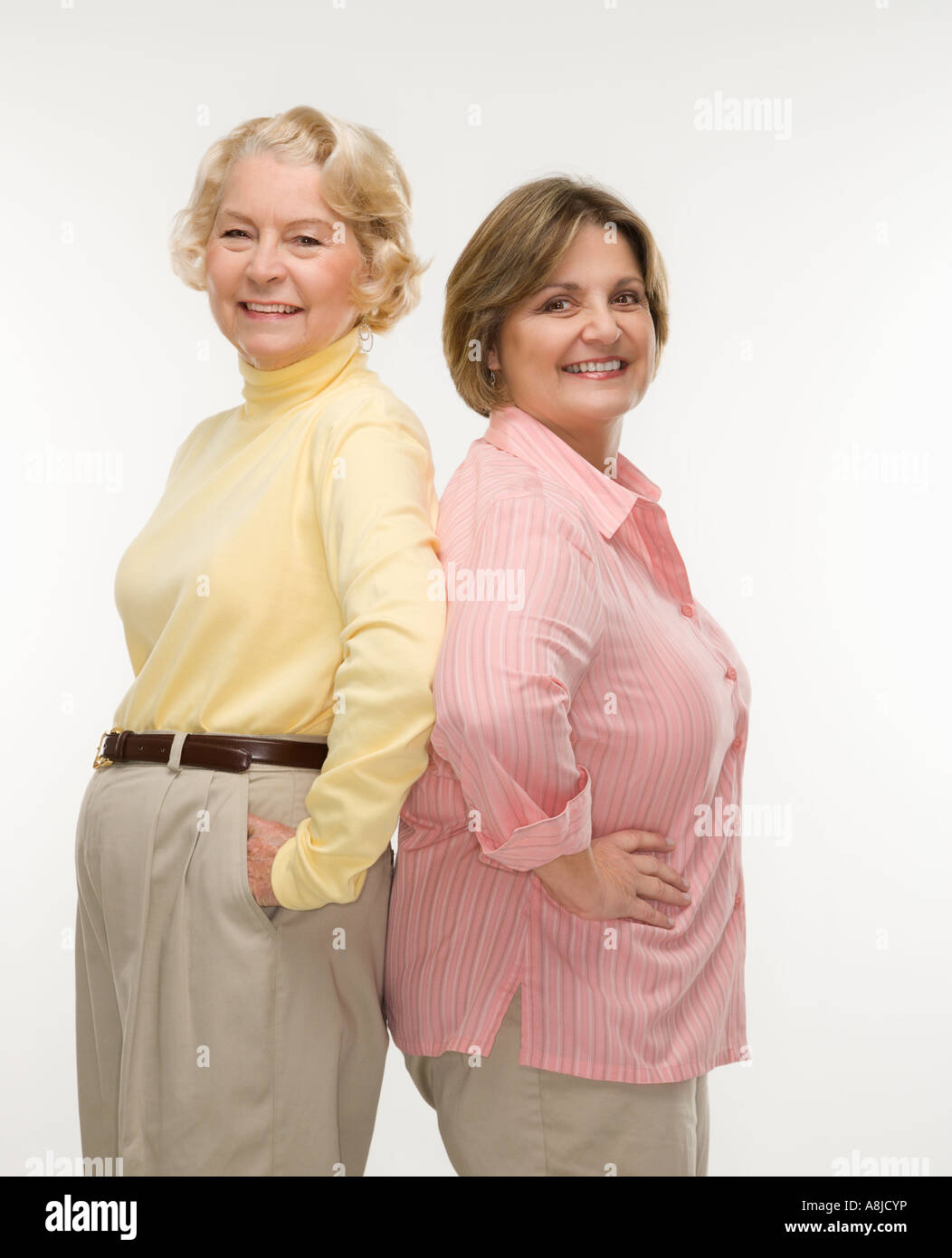 Caucasian senior woman and middle aged woman standing back to back ...