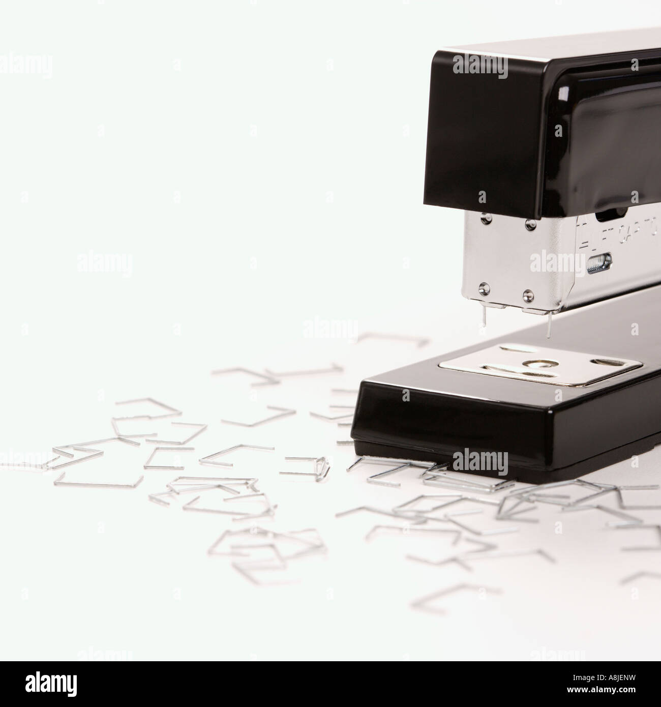 Black stapler on white background surrounded by individual staples ...