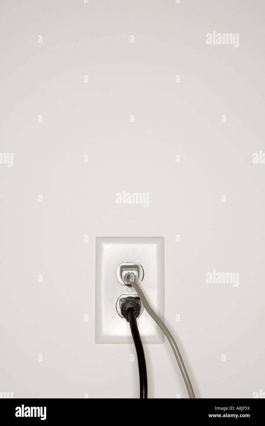 Two cords plugged into electrical wall outlet Stock Photo - Alamy