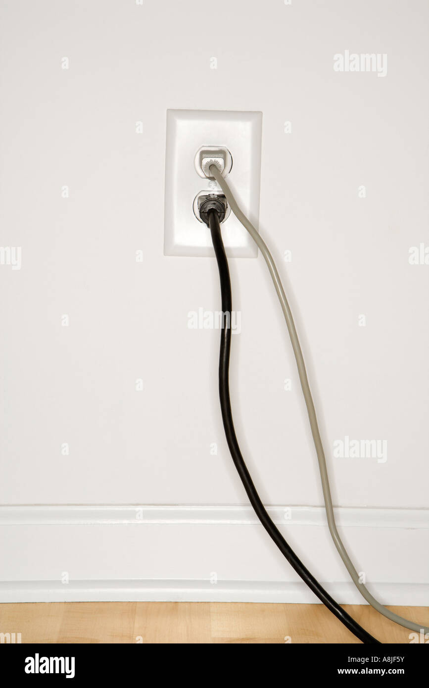 Two cords plugged into electrical wall outlet Stock Photo - Alamy