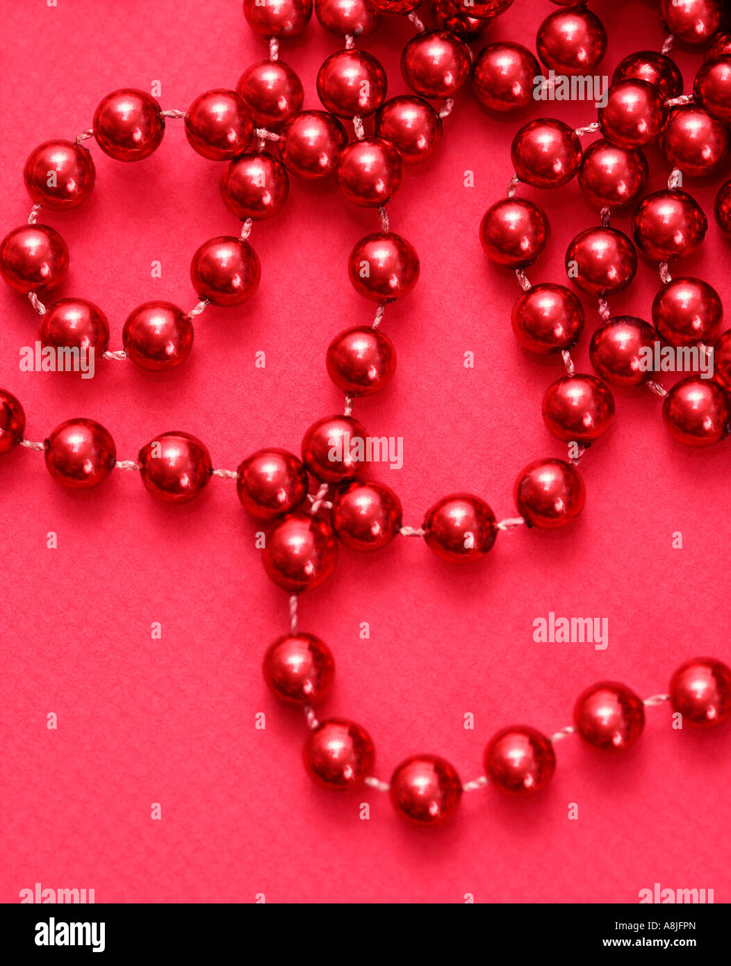 String of red beads on red background Stock Photo - Alamy