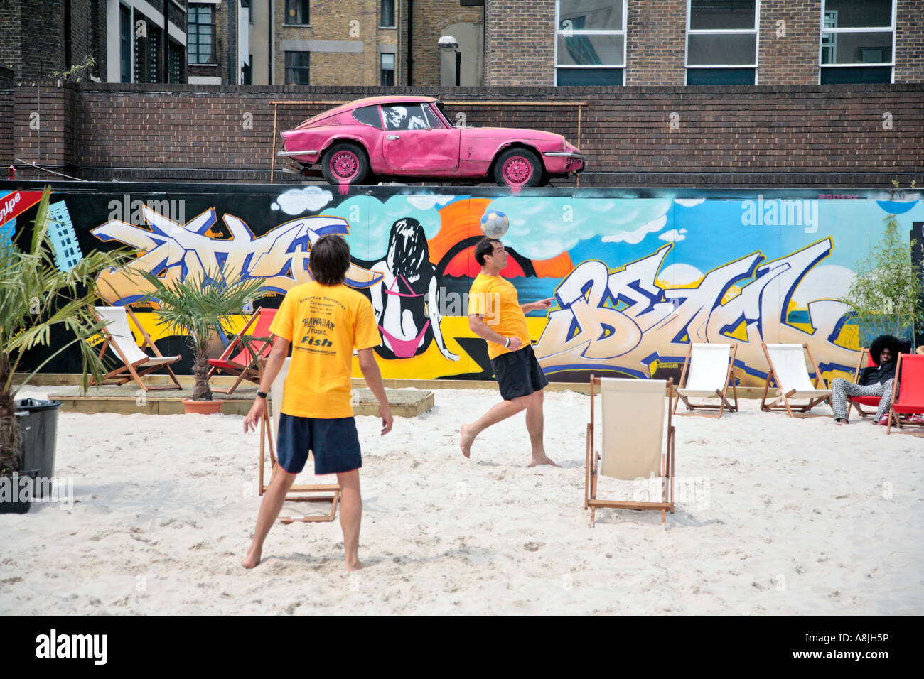 two men juggle a football on a city beach in brick lane, east london ...