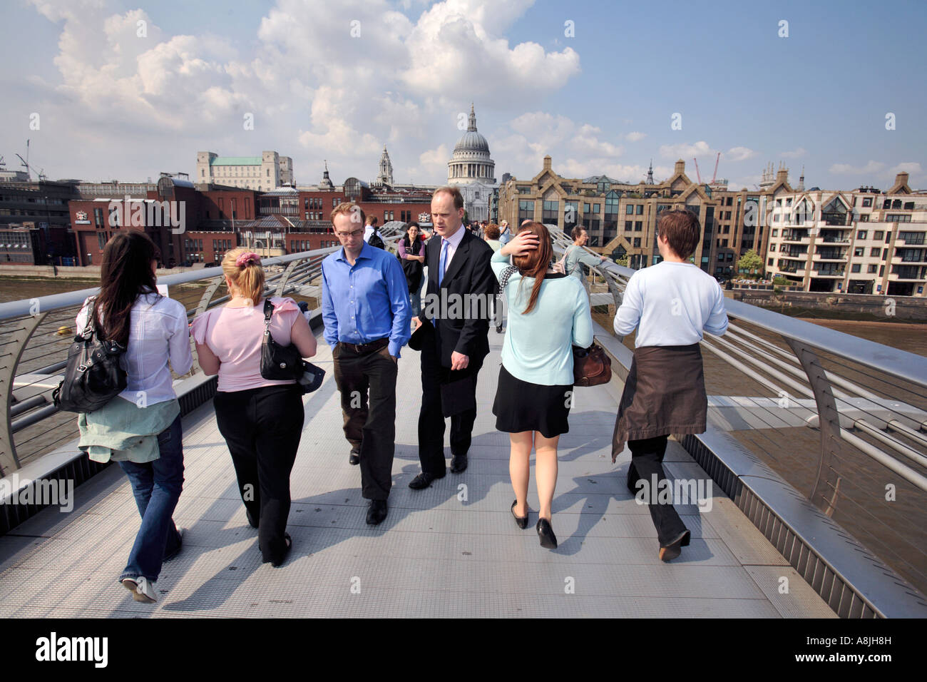 A group of people walking over the Millenium Bridge in London Stock ...