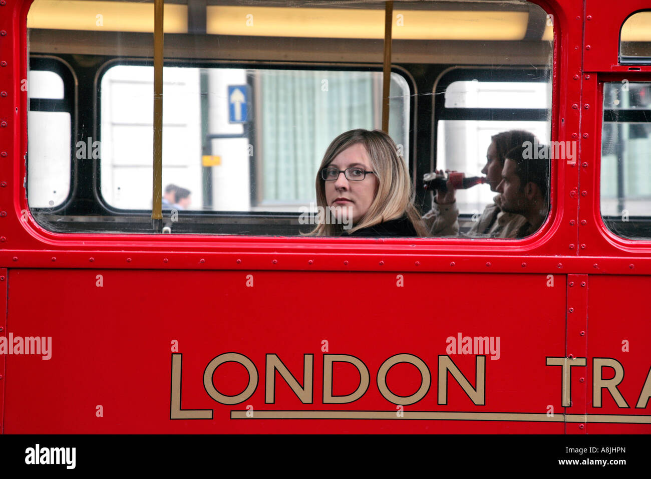 a woman looks out of the window of a routemaster red bus in London ...