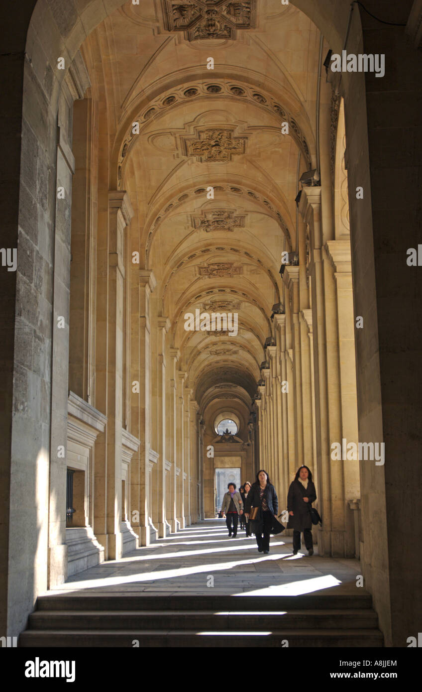 Tourists walk through the Vaulted walkway through to the Louvre Museum ...