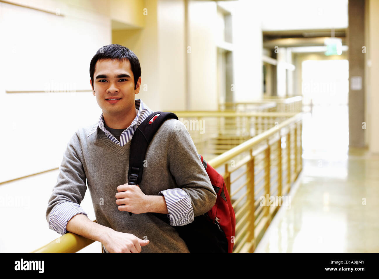Portrait of a young man leaning against the railing of a corridor Stock ...