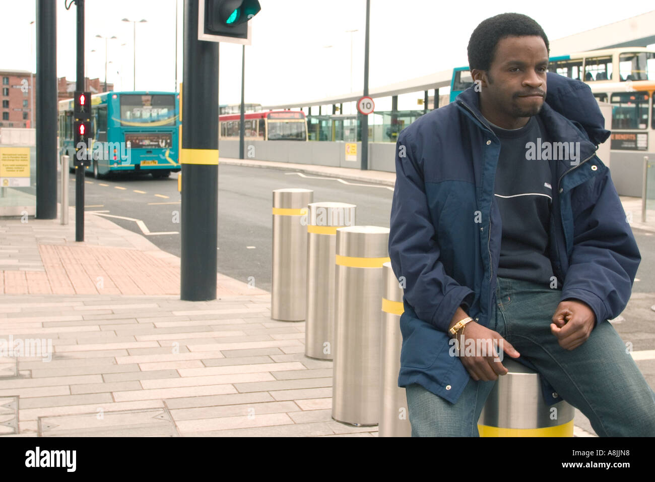 african negro male sitting on bollard waiting for bus Stock Photo - Alamy