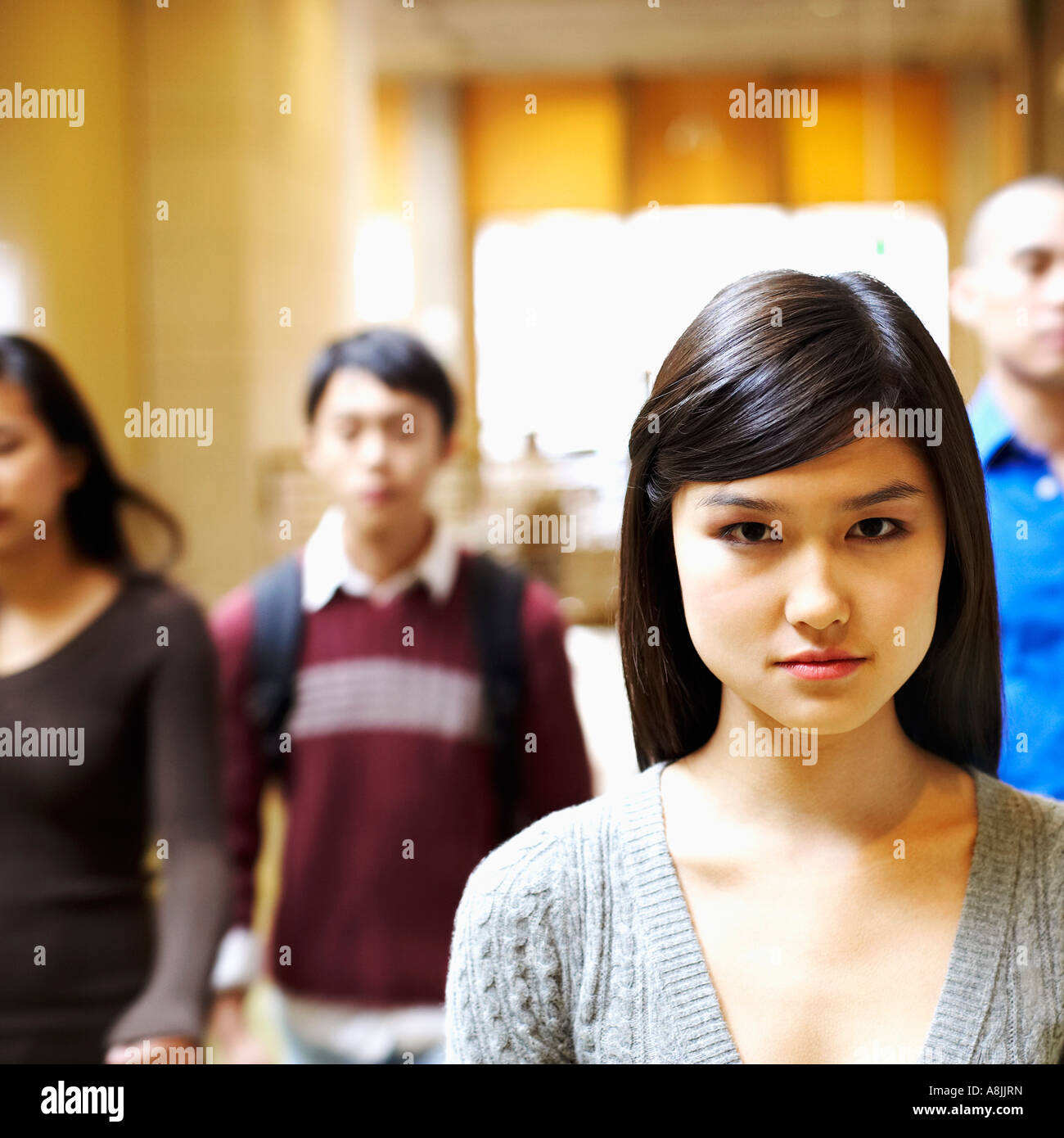 Portrait of a young woman walking in the corridor with three people ...