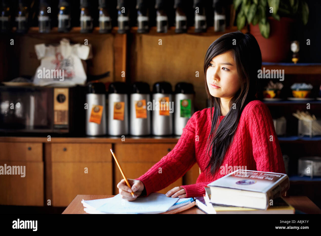 Young woman writing on a sheet of paper and thinking Stock Photo - Alamy
