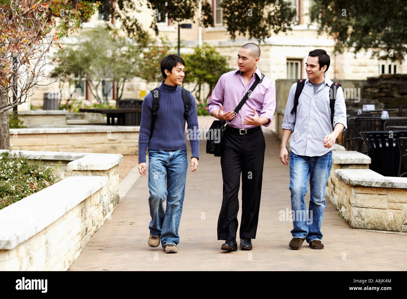 Three young men walking in a college campus and talking Stock Photo - Alamy