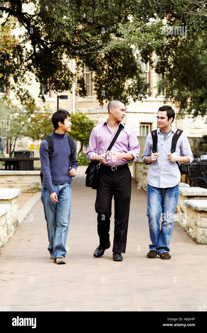 Three young men walking in a college campus and talking Stock Photo - Alamy