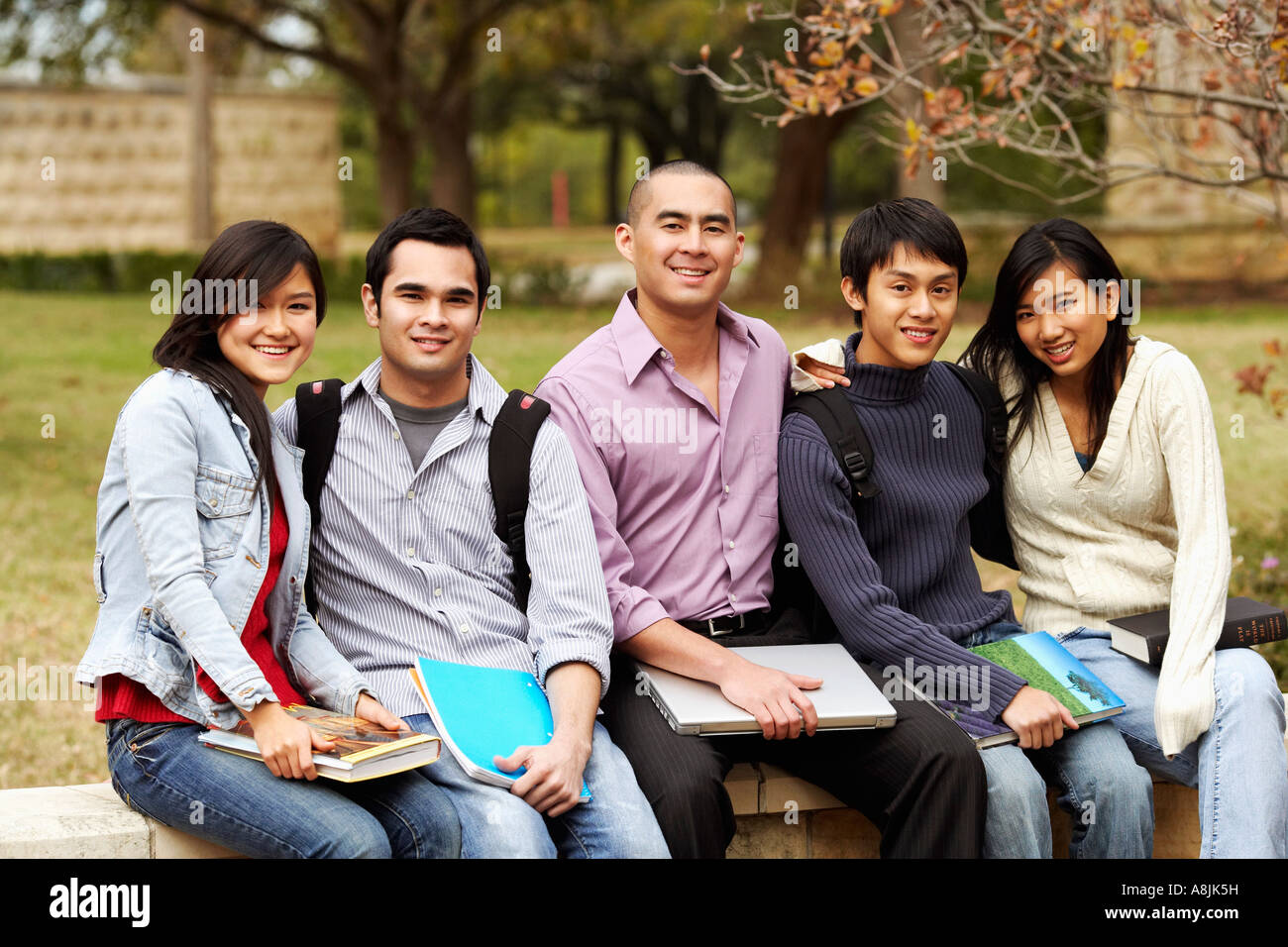 Portrait of five college students sitting together in a college campus ...