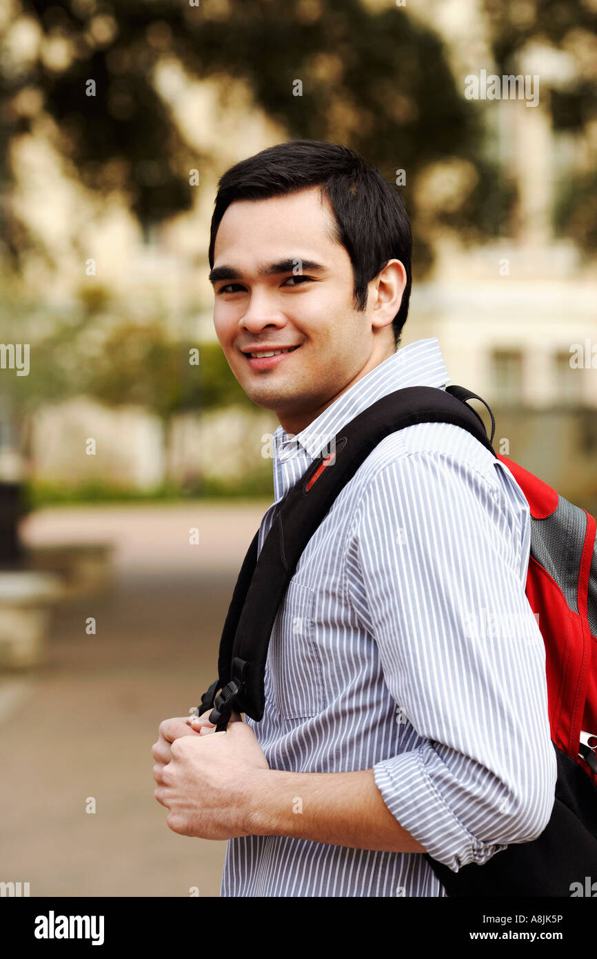Portrait of a young man carrying a backpack and smiling Stock Photo - Alamy