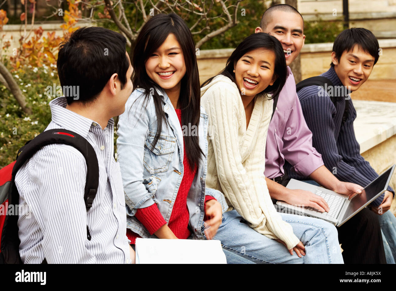 Five young college students sitting together in a college campus and ...