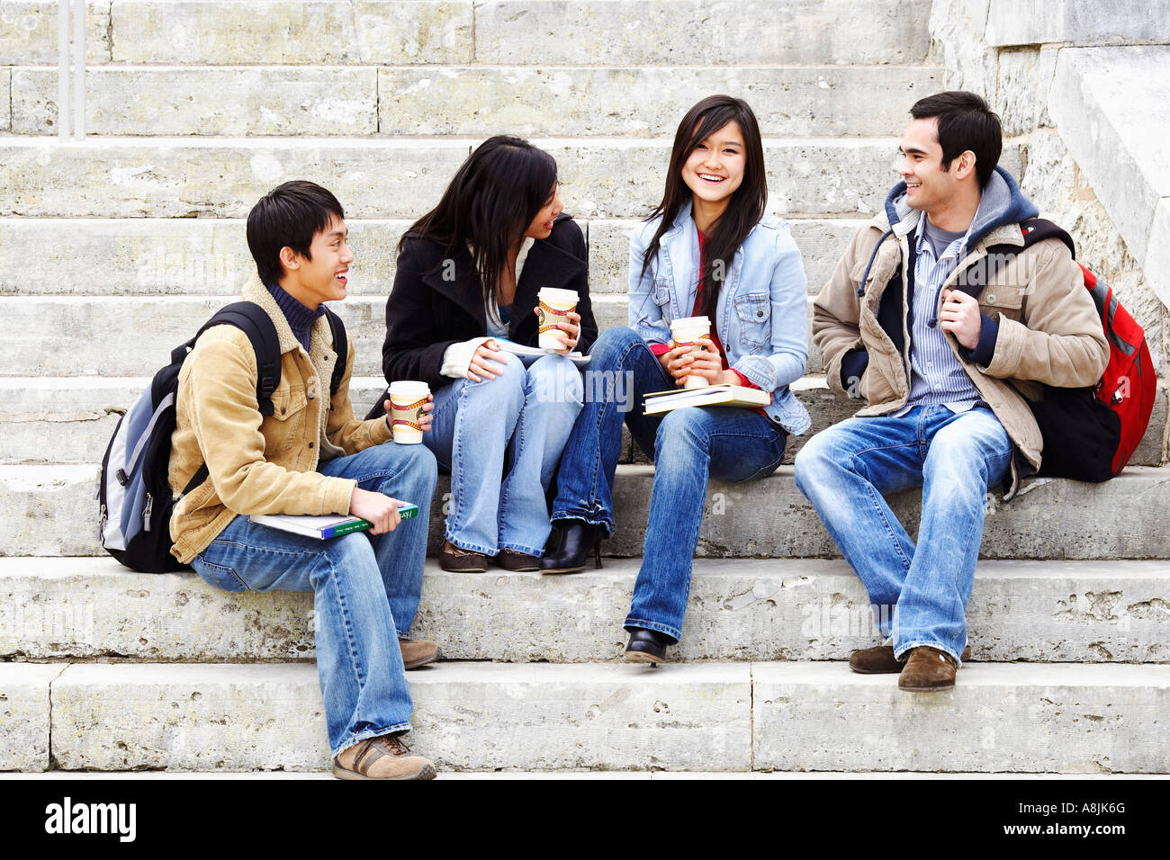 Four college students sitting on steps and smiling Stock Photo - Alamy