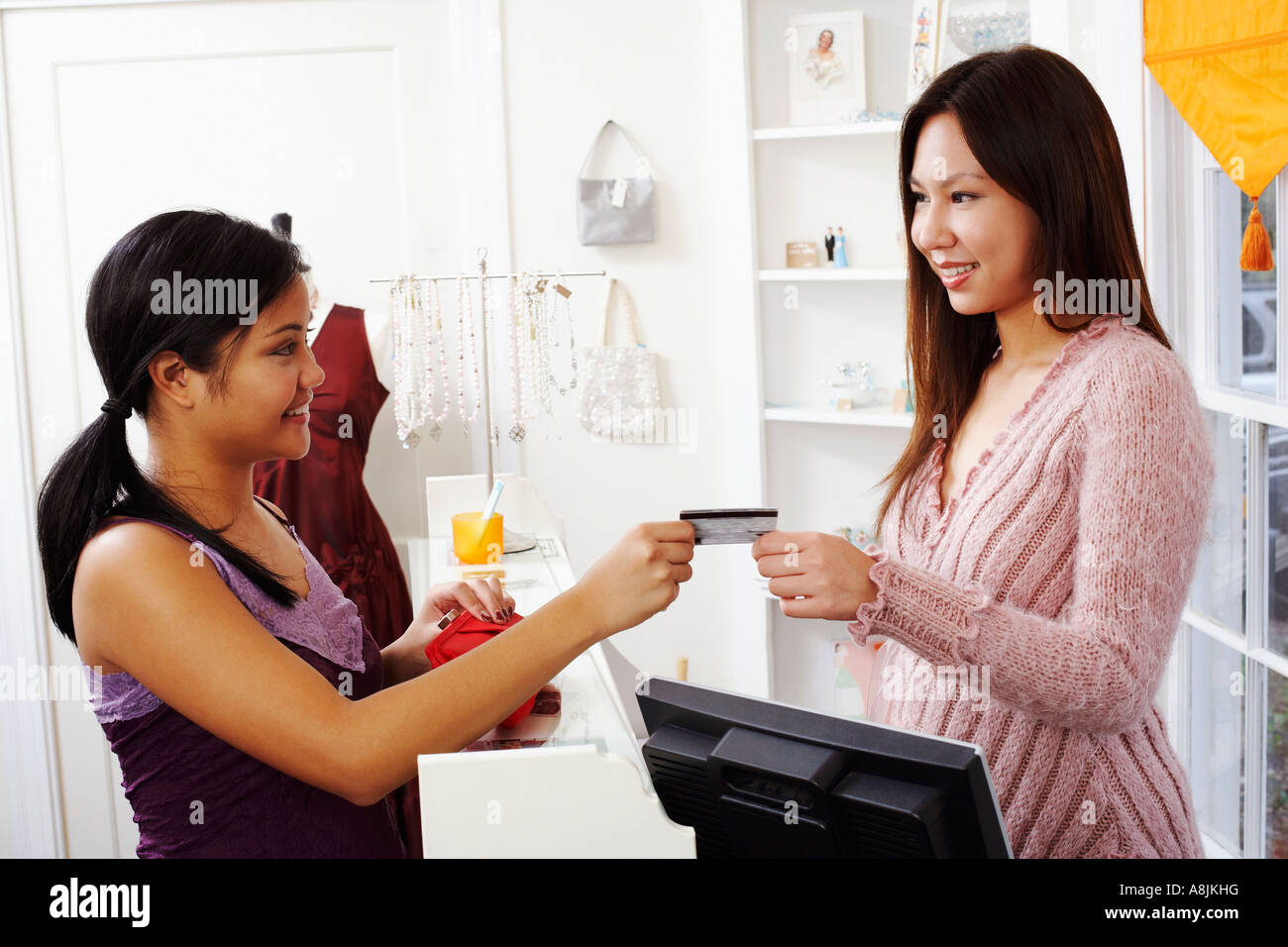 Side profile of a young woman giving a credit card to a sales clerk ...
